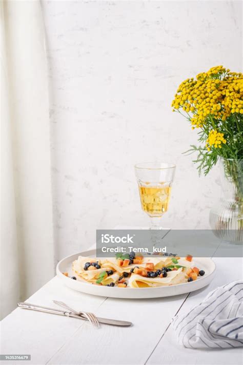 접시에 블루 베리 복숭아 민트를 곁들인 팬케이크 흰색 나무 테이블입니다 밝은 배경입니다 노란 꽃과 노란 음료가있는 소박한 테이블 제공 건강한 식생활에 대한 스톡 사진 및