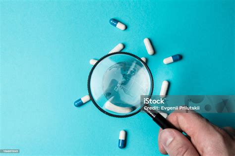 청록색 배경에 돋보기 아래 글로브와 알약 의료의 감독하에 지구의 건강을 모니터링합니다 사람들의 건강은 의사의 통제하에 있습니다 근접 촬영 세계지도에 대한 스톡 사진 및 기타