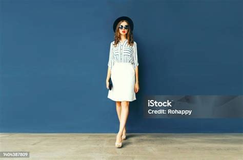 흰색 줄무늬 셔츠 검은 둥근 모자 진한 파란색 배경에 핸드백 클러치를 착용 한 전체 길이 아름다운 젊은 여성 20 29세에 대한 스톡 사진 및 기타 이미지 Istock