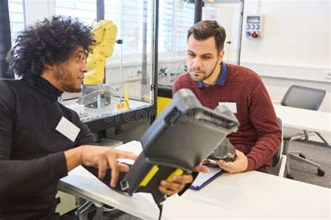 Two Engineers Programming A Robotic Arm In A Modern Training Facility