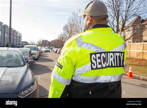 Security Guard Conducting Access Control And Traffic Control Around A Community Building Stock