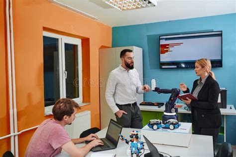 A Group Of Colleagues Working Together In A Robotics Laboratory Focusing On The Intricate