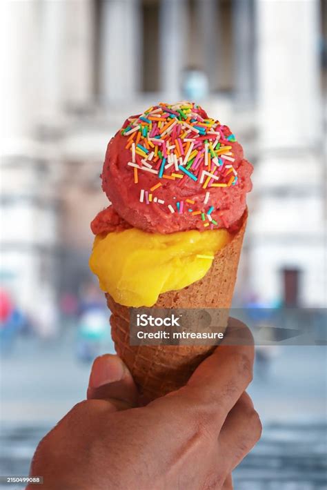 와플 콘 망고와 딸기 젤라토 아이스크림 두 스쿱 여러 가지 빛깔의 설탕 뿌리기 생생한 컬러 배경 전경에 초점을 맞춘 알아볼 수 없는 사람의 클로즈업 이미지 건강에 좋지 않은