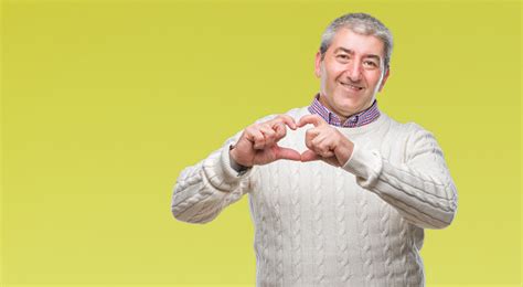 잘생긴 수석 남자 마음 기호와 손으로 모양을 보여주는 사랑에 웃 고 고립 된 배경 위에 겨울 스웨터를 입고 낭만적인 개념입니다 가을에 대한 스톡 사진 및 기타 이미지