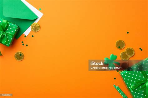 성 패트릭의 날 개념 빈 공간이 있는 격리된 주황색 배경에 편지 금화 클로버 빨대와 색종이가 있는 녹색 선물 상자 봉투의 상위