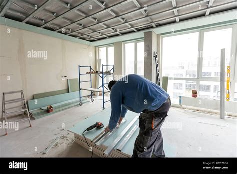 Construction Worker Assemble A Suspended Ceiling With Drywall And