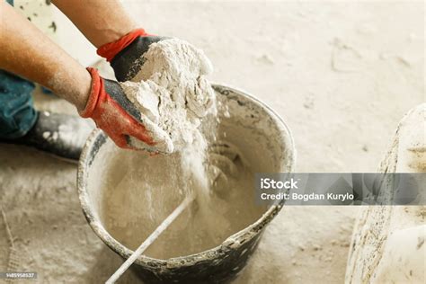 석고 석고를 벽으로 만들기 위해 물과 석고 석고를 혼합하는 작업자 집과 가정 개조 개념의 건설 치장 벽토 믹스와 핸디맨 손으로 양동이를 닫습니다 개선에 대한 스톡 사진 및