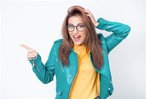 흰색 배경에 고립 된 녹색 가죽 재킷을 입고 텍스트 또는 이미지에 대한 공간을 복사하기 위해 집게 손가락으로 가리키는 젊은