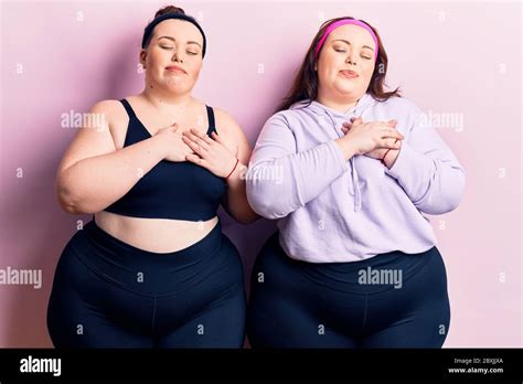 Young Plus Size Twins Wearing Sportswear Smiling With Hands On Chest