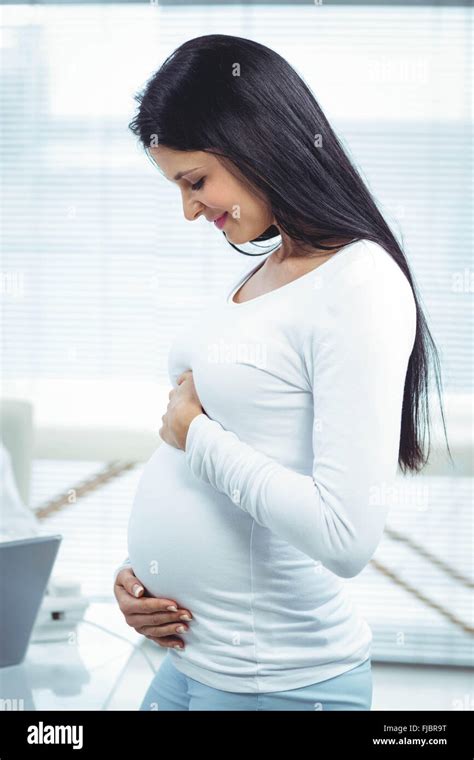 Pregnant woman holding her stomach Stock Photo - Alamy