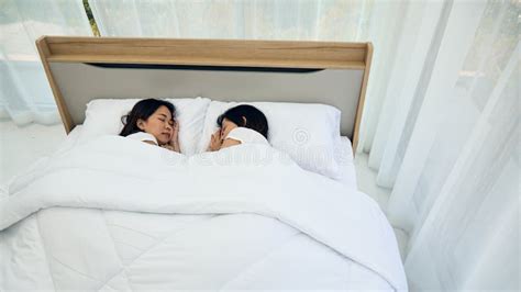 Two Women Peacefully Sleeping Side By Side In Bed Covered With White