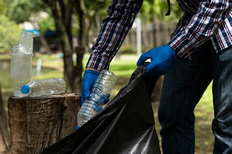 자원봉사자들은 자선 단체를 위한 환경 폐기물을 수거하는 데 도움을 줍니다 플라스틱 병을 집어 들고 남자는 세계에서 쓰레기를 수집 숲을 청소합니다 공공 정원에서 쓰레기를