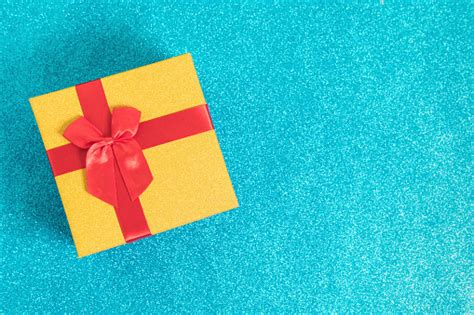 반짝이는 푸른 반짝이 배경에 활이 달린 황금 빛나는 선물 상자 다가오는 휴일에 축하크리스마스와 새해 배경 기프트 교환 플랫 레이 맨 위 보기입니다 복사 공간을 참조하십시오