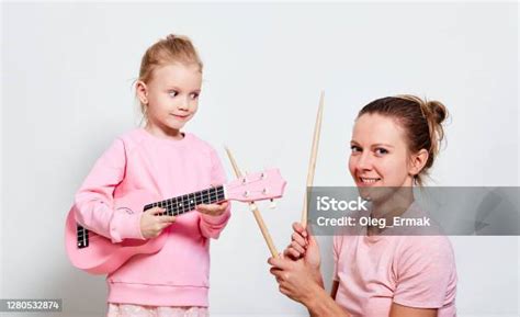 용어머니와 예쁜 딸은 악기 중립적 인 회색 배경에서 연주 우쿨렐레와 나무 드럼스틱을 들고 함께 재미있는 시간을 보내고 2명에 대한 스톡 사진 및 기타 이미지 Istock