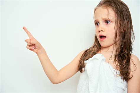 젖은 머리를 가진 작은 유치원 소녀는 흰색 배경에 싸여 얼굴 표정 데 손가락으로 흰색 수건을 가리키는 사진 Contingency Plan에 대한 스톡 사진 및 기타 이미지