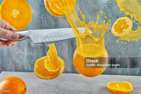 갓 자른 오렌지 부양 칼이 오렌지를 자른다 오렌지는 다른 방향에서 주스와 주스 흐름을 뿌린다 파란색 배경에 오렌지의 비행 조각 감귤류 과일에 대한 스톡 사진 및 기타 이미지