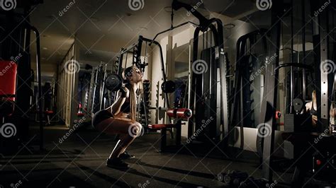 Девушка делая сидеть на корточках с штангой в спортзале Стоковое Фото изображение