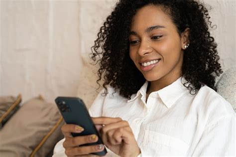 편안한 소파에서 휴식을 취하고 스마트 폰을 손에 들고 행복한 아프리카 계 미국인 여성 20 24세에 대한 스톡 사진 및 기타