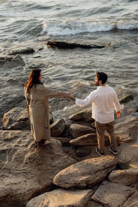 바다에서 손을 잡고 있는 로맨틱한 커플 · 무료 스톡 사진