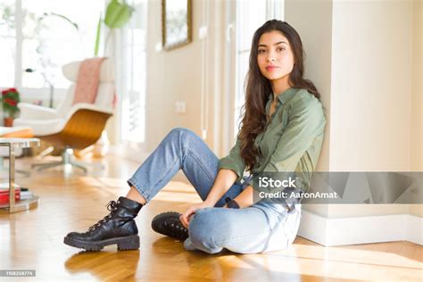 젊은 아름다운 여자는 얼굴에 심각한 표정으로 집에서 바닥에 앉아있다 카메라를 보는 간단하고 자연스러운 갈색 머리에 대한 스톡 사진 및 기타 이미지 Istock