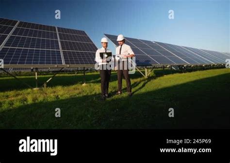 Two Engineers In Helmets And Formal Attire Use A Laptop And Documents To Evaluate The