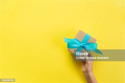 여자 손 블루 리본으로 종이에 싼된 발렌타인 또는 다른 휴일 수 제 선물을 제공합니다 선물 상자 노란 테이블에 선물 복사 공간 평면도의 장식 공예에 대한 스톡 사진 및 기타