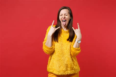 미친 젊은 여 자가 제스처를 빨간색 배경에 고립 눈을 폐쇄 유지 혀를 보여주는 무거운 금속 바위 기호를 묘사 사람들은 진심으로 감정 라이프 스타일 개념입니다 복사 공간을