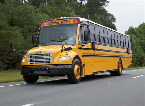 Download Traveling School Bus Across Road With Trees Wallpaper