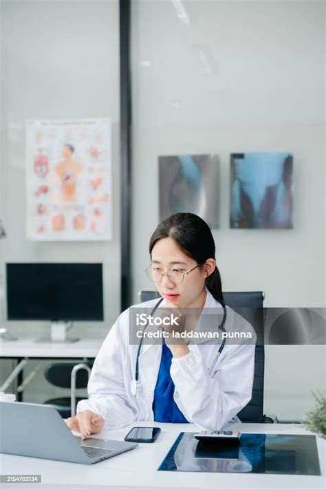 아름다운 의사 의사가 사무실 병원의 테이블에 앉아 있습니다 매력적인 치료사 여성 시술사 약사 웃는 얼굴로 정제를 사용 20 24세에 대한 스톡 사진 및 기타 이미지 Istock