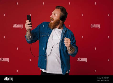Ginger White Man Singing And Dancing While Listening Music Isolated Over Red Background Stock