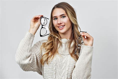 베이지 색 스웨터를 입은 여성이 안경을 쓴다 소녀는 흰색 벽의 배경에 안경을 보인다 안경에 대한 스톡 사진 및 기타 이미지 안경 20 24세 귀여운 Istock