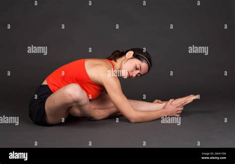 Female Gymnast In A Red Shirt And Black Shorts Stretching And Warming
