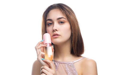우아한 누드 바디수트를 입은 아름다운 섹시한 여성이 손에 병을 들고 격리된 흰색 배경에 있는 패션 모델 소녀의 패션 뷰티 초상화 프리미엄 사진
