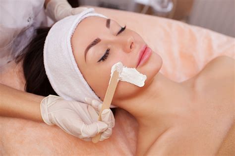 젊은 여자의 얼굴에 막대기로 마스크를 적용 하는 클렌징과 피부 보습의 절차에 대 한 미용사 가꿔주기에 대한 스톡 사진 및 기타