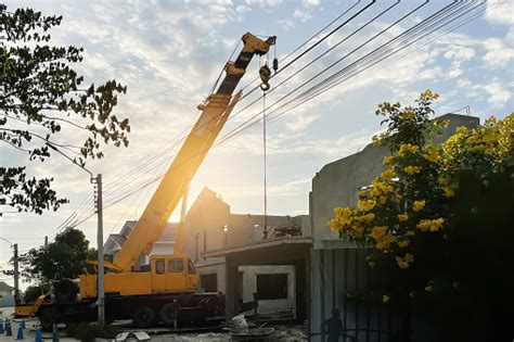 건설 산업 및 비즈니스 기술 배경을위한 황혼 시간에 주택 프로젝트를위한 현장 건설 리프팅 프리 캐스트 바닥 패널을 작업하는 트럭 크레인 기계의 이미지 이동식 크레인에 대한