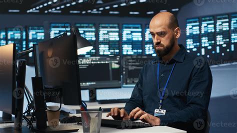 System Operator Overseeing Server Room Typing Code On Desktop Pc