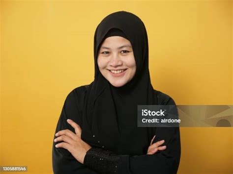 십자가의 팔 자신감 있는 제스처 성공적인 사업가로 친근한 미소를 짓는 히잡을 입은 아시아 무슬림 여성 노란 배경에 맞서 경영자에 대한 스톡 사진 및 기타 이미지 Istock