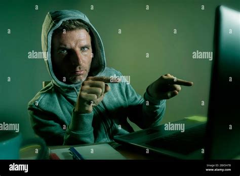 dangerous looking hacker man in hoodie hacking internet computer system