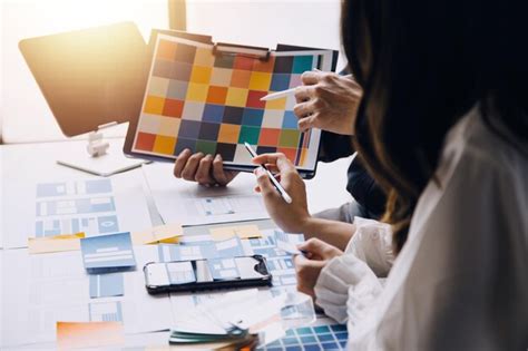 Ux 개발자 및 Ui 디자이너가 최신 사무실에서 고객 브리프 및 색상 코드를 사용하여 테이블의 모바일 앱 인터페이스 와이어프레임 디자인에 대해 브레인스토밍하는 닫기