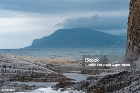 폭풍우가 몰아치는 바다를 배경으로 기둥 현무암으로 형성된 흐린 바위 같은 바닷가 쿠릴 제도의 해안 풍경 쿠나시르 섬에 대한 스톡 사진 및 기타 이미지 Istock