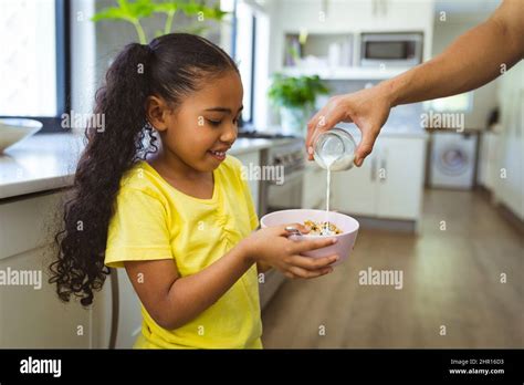 Cropped hand of father pouring milk in cereal bowl for multiracial ...