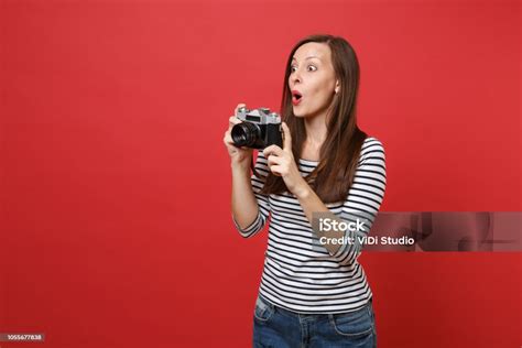 젊은 여 자가 입 벌리고 유지 하는 복고풍 빈티지 사진 카메라 들고 놀 밝은 빨간 벽 바탕에 고립 된 보고 놀 랐 다 사람들이 진심으 감정 라이프 스타일 개념 복사 공간을