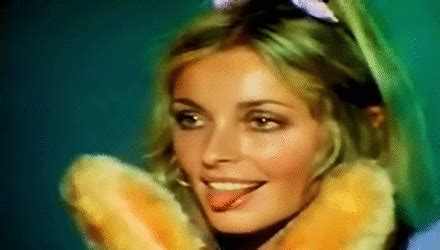 A Woman With Green Hair Is Smiling And Wearing A Yellow Fur Collar Around Her Neck