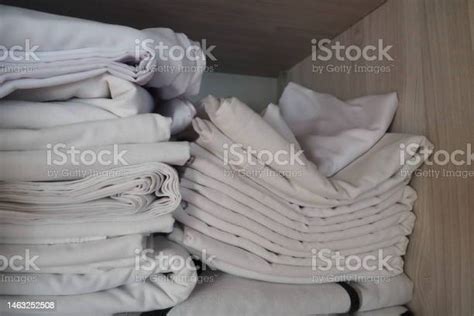 흰색 침구는 옷장에 쌓여 있습니다 린넨 옷장의 내부 내용물 가정 조직 수면을위한 위생 조건 반쯤 열린 흰색 옷장이나 옷장에 있는 직물과 침대 시트 베개커버에 대한 스톡 사진