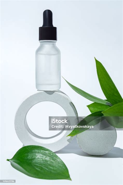 하얀 둥근 연단에 피펫이 있는 젖빛 유리 화장품 병 천연 루스커스 가지로 제품 포장 펩타이드가 있는 노화 방지 세럼 화장품 모형 스파 개념 0명에 대한 스톡 사진 및 기타