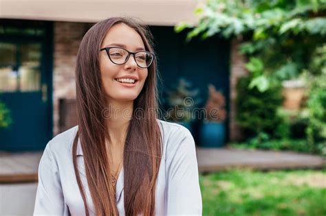 Portrait Of A Young Smiling Brunette Girl In Glasses Against The