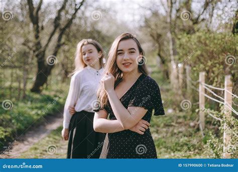 Portrait Of Two Beautiful Young Sisters In The Green Spring Garden