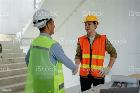 다민족 엔지니어가 서류 작업 및 평면도 도면 계약 및 계약 개념에 대한 비용 추정을 위해 거래 및 측정에 대해 브레인스토밍합니다