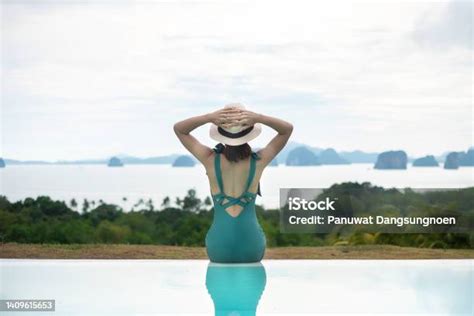 바다 자연 배경에 대한 고급 수영장 호텔에서 수영 녹색 수영복을 입은 행복한 여성 모자를 쓴 젊은 여성은 열대 리조트에서 즐길 수 있습니다 휴식 여름 여행 휴일 휴가 개념