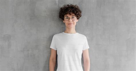 텅 빈 흰색 면 티셔츠를 입고 회색 질감의 벽에 서서 포즈를 취하는 매력적인 젊은 여성 사진 Unsplash의 초상 이미지